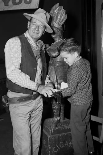 John Wayne smiling by cigar store Indian showing gun to kid 24x36 ...