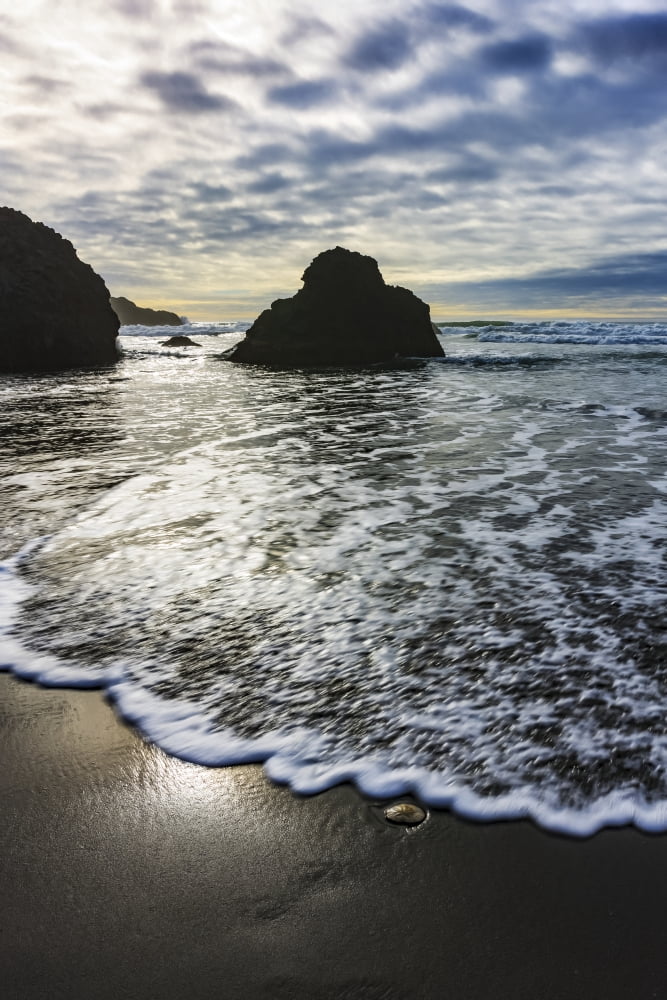 Silhouetted coastline and rock formations along the Oregon coast at ...