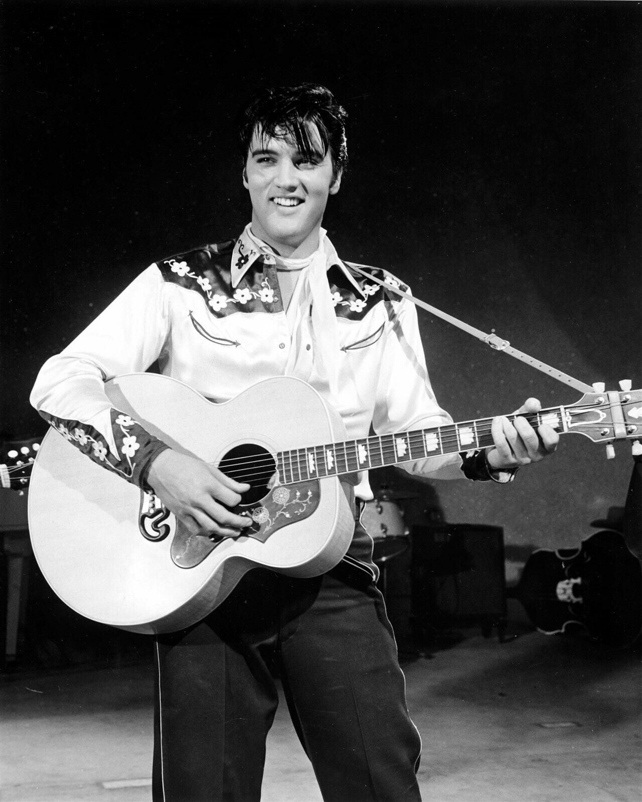 Elvis Presley in western style shirt & scarf playing guitar on stage ...