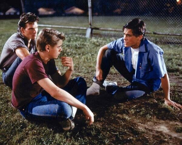 The outsiders Patrick Swayze C. Thomas Howell Rob Lowe sit on grass ...