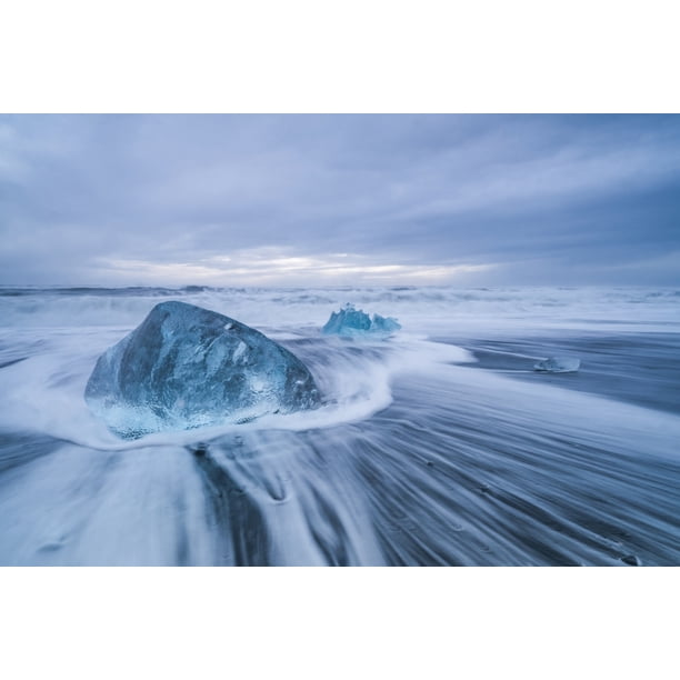 Large ice block laying on the shores of Southern Iceland while waves ...
