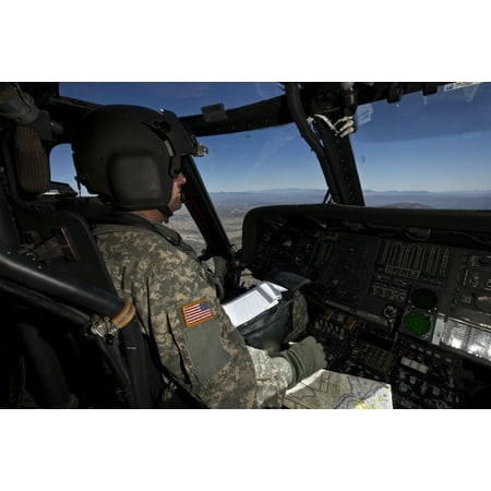 Pilot operating the cockpit of a UH-60 Black Hawk helicopter while en ...