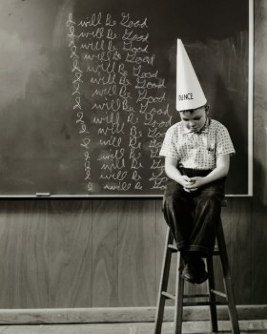 Boy wearing a dunce cap sitting in front of a blackboard Poster Print ...