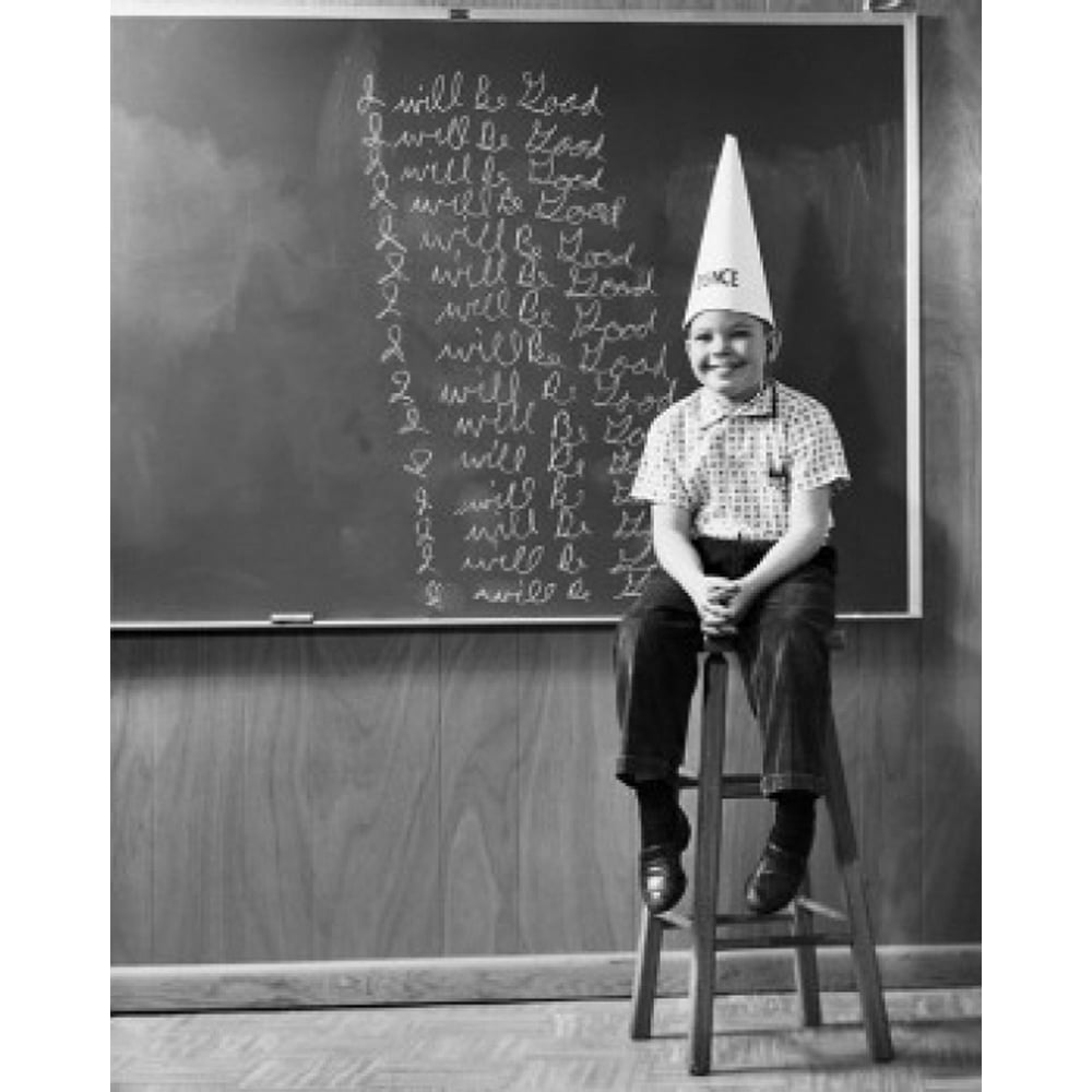 Boy wearing a dunce cap sitting in front of a blackboard Poster Print ...