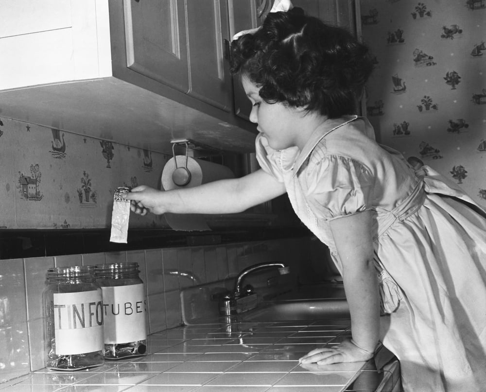 A Little Girl Deposits A Tooth Paste Tube In A Household Collection Jar ...