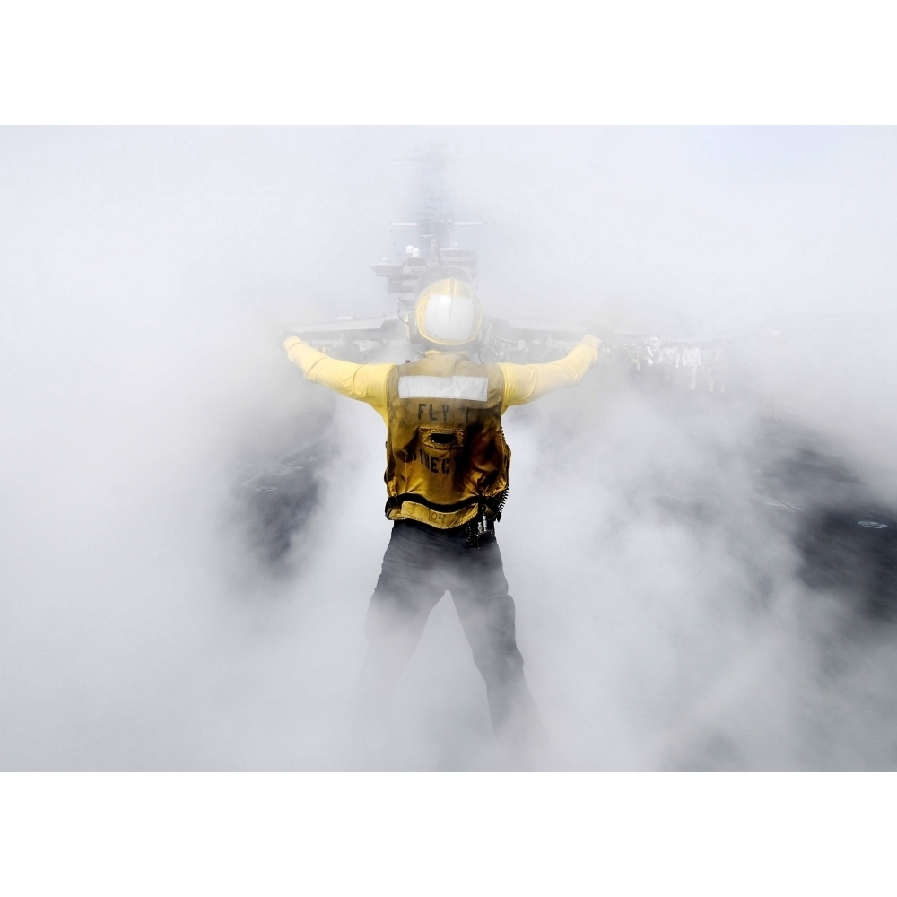 A U.S. Navy flight deck director directs an EA-6B Prowler onto a steam ...