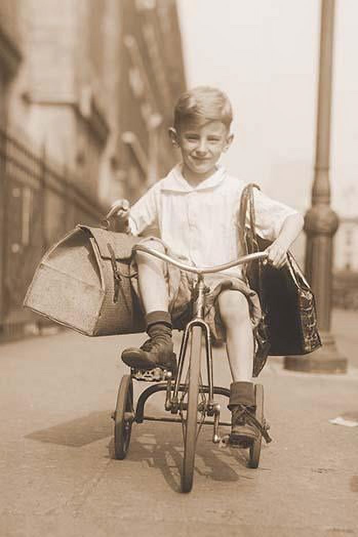 A photograph of a little boy peddling his tricycle while holding two ...