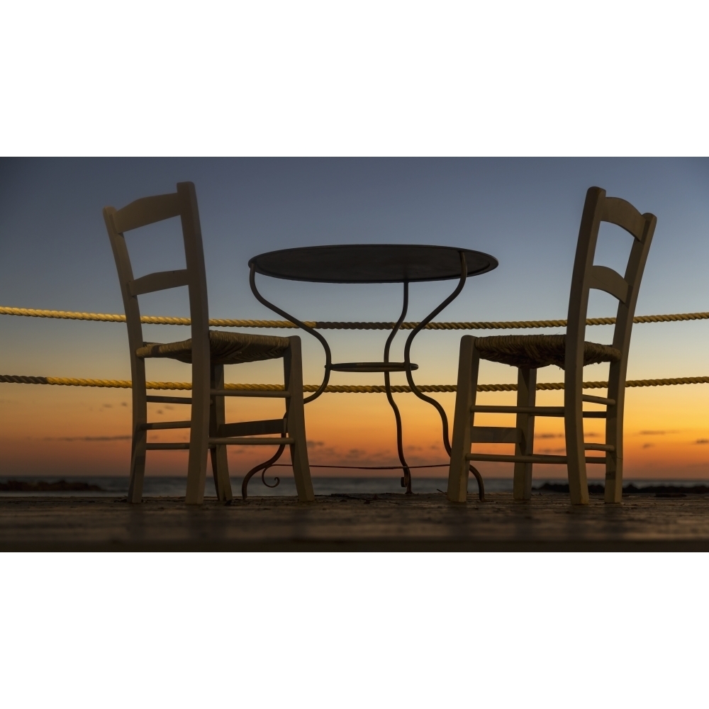 A table and chairs on a patio with a view of a colourful sunset; Paphos ...