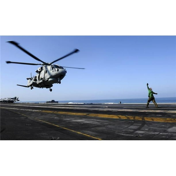 Airman directs an EH-101 Merlin helicopter onto the flight deck of USS ...
