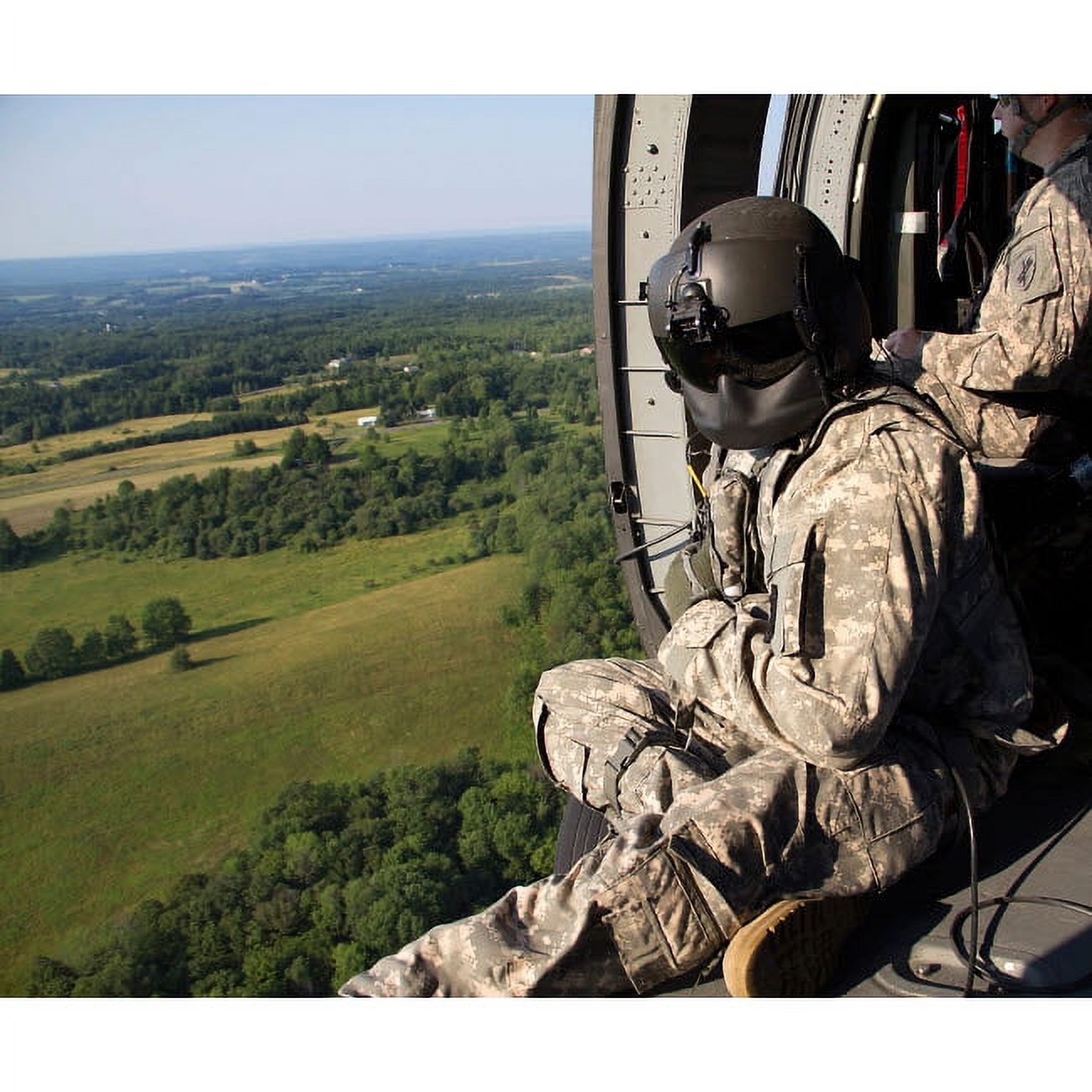 An Army crew chief looks out the door of a UH-60 Black Hawk helicopter ...