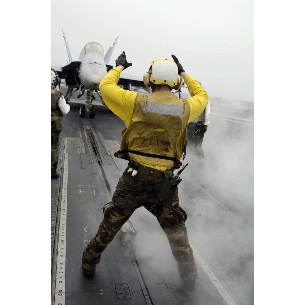 An aircraft director signals a F/A-18C Hornet on the flight deck of USS ...