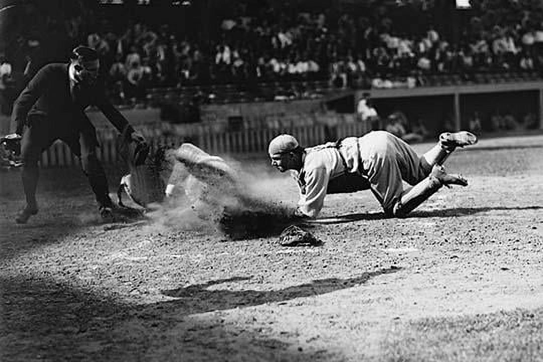 Baseball Player raises the dust as he tries to score from third base at ...