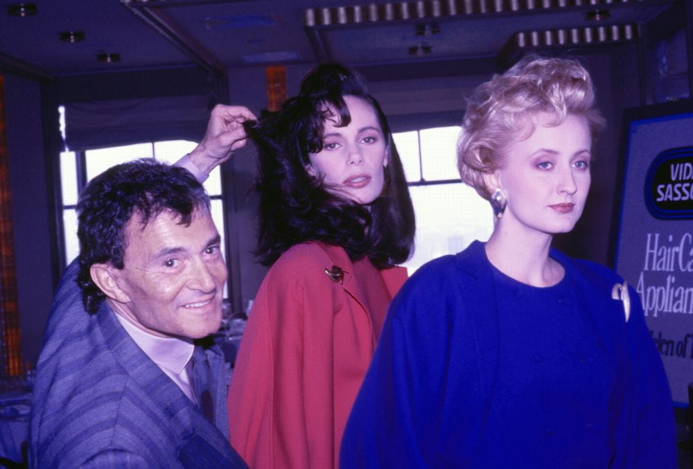 British hairstylist Vidal Sassoon, wearing a grey striped suit, smiling ...