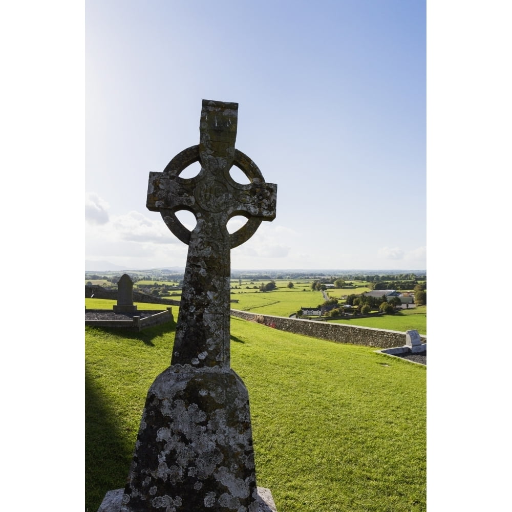 Celtic cross on grassy hill with stone wall under blue sky; Cashel ...