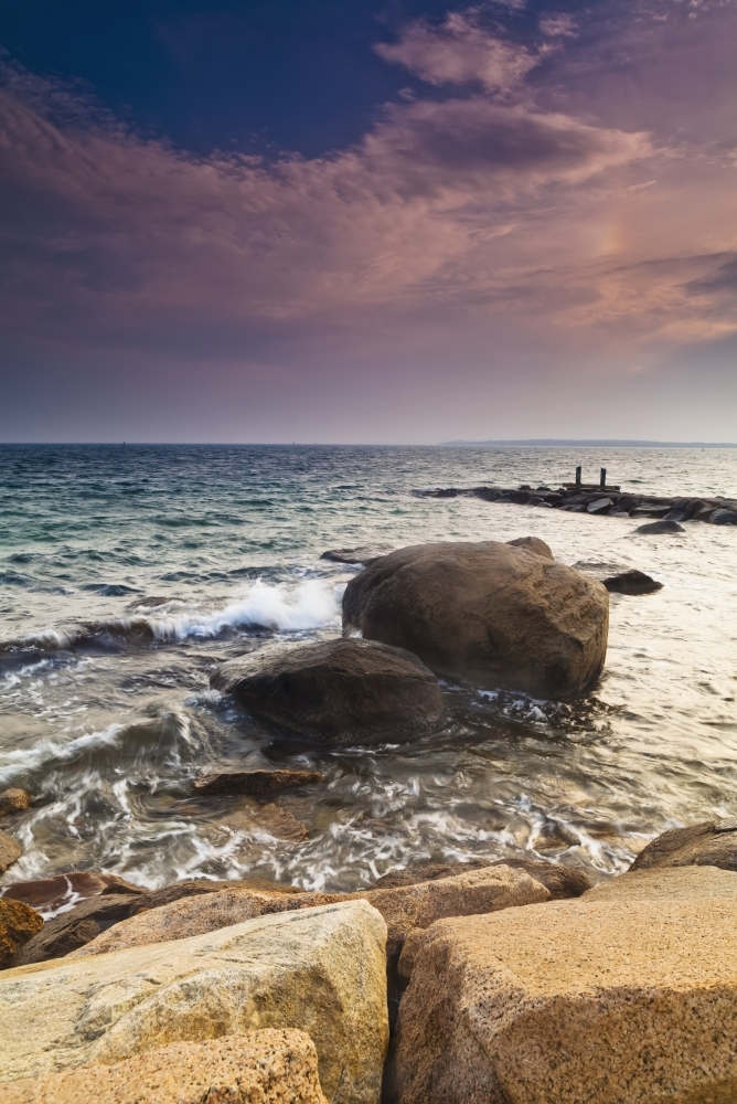 Glowing pink clouds at sunset and rocks along the coast; Falmouth ...