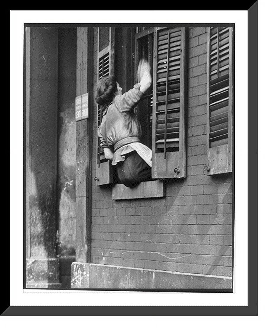 Historic Framed Print, [Woman seated on window sill and washing window ...