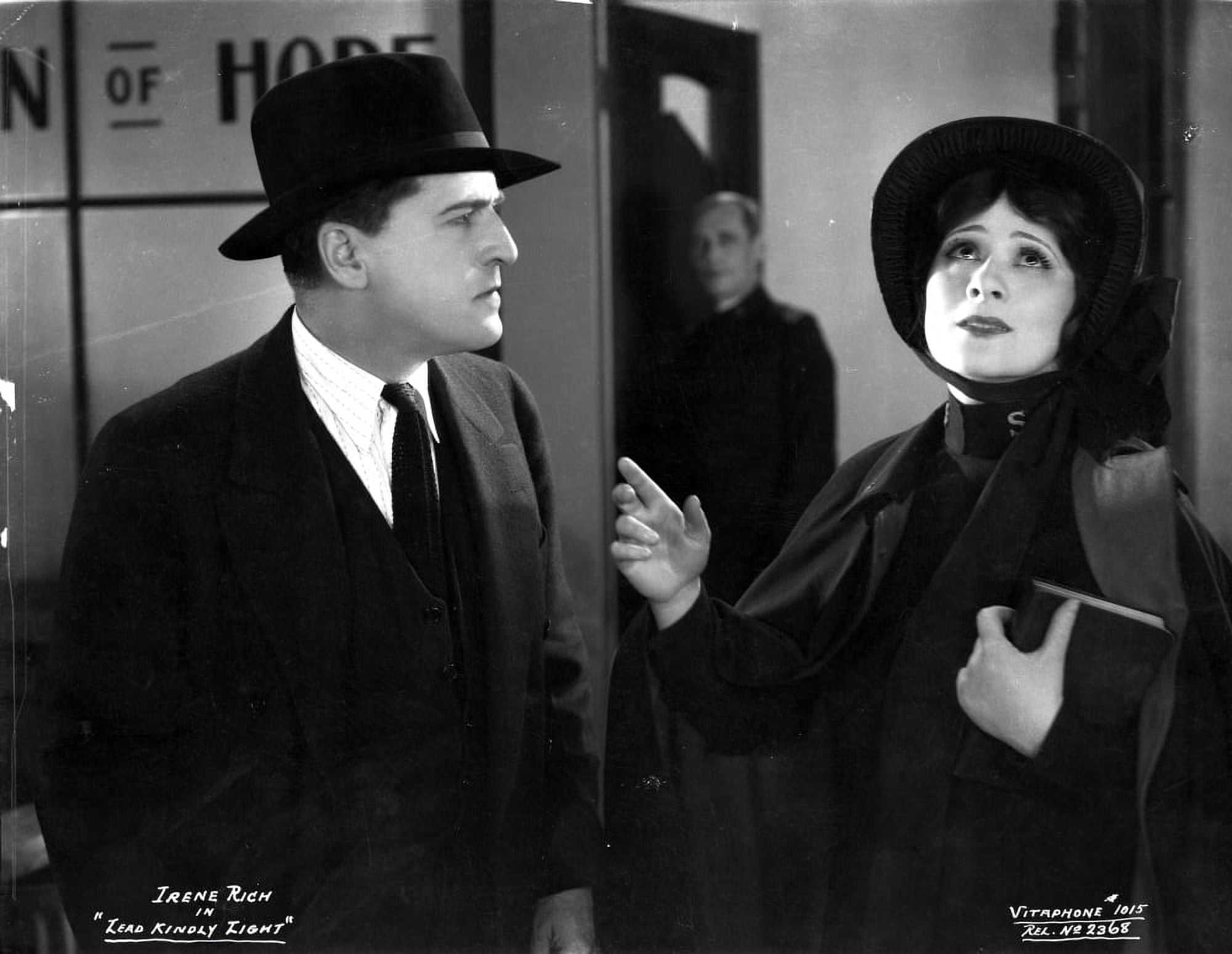 Irene Rich wearing a Black Dress Holding a Book and Talking to a Man ...