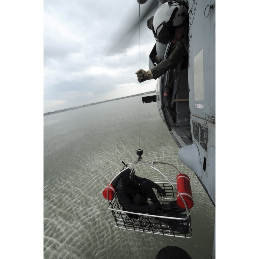Naval Air Crewman hoists a rescue basket into an MH-60S Sea Hawk ...