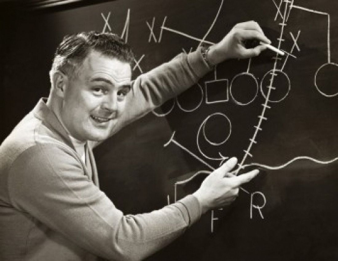 Portrait of a football coach explaining game play on the blackboard ...