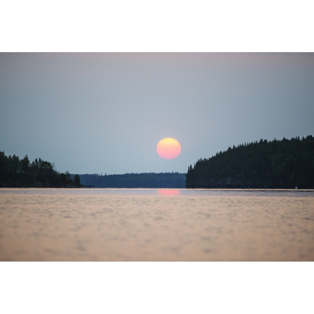 Posterazzi A Red Sun Setting Over The Forest with A Lake Reflecting The ...