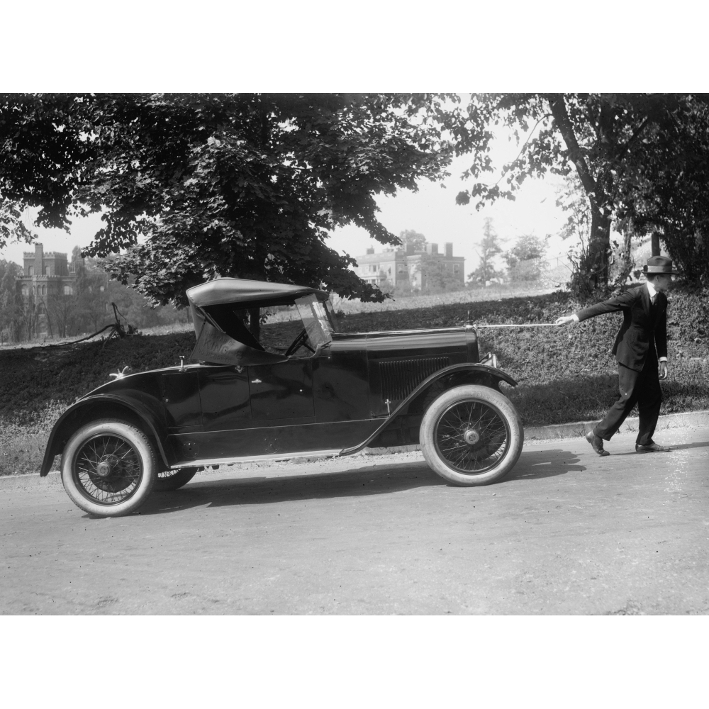 Suited man looks like he is pulling a coupe up an incline by a string ...