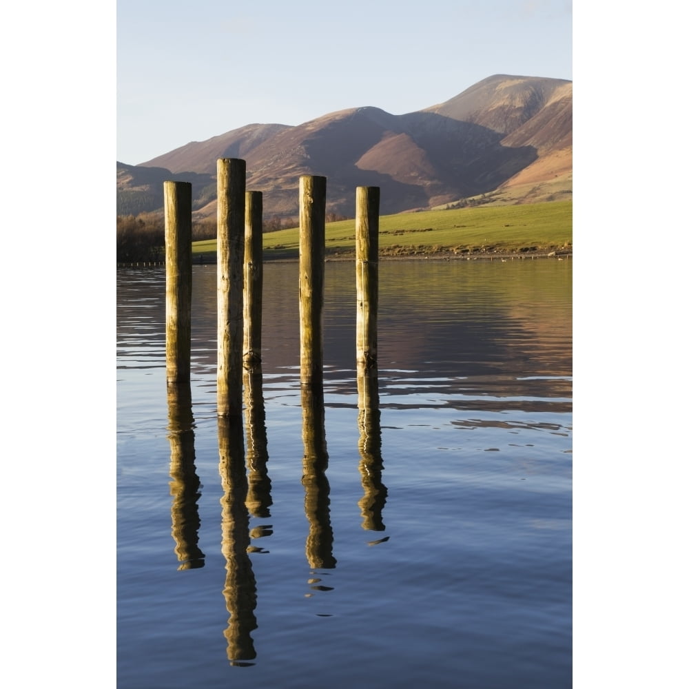 Wooden posts reflected in tranquil after with mountains the the ...