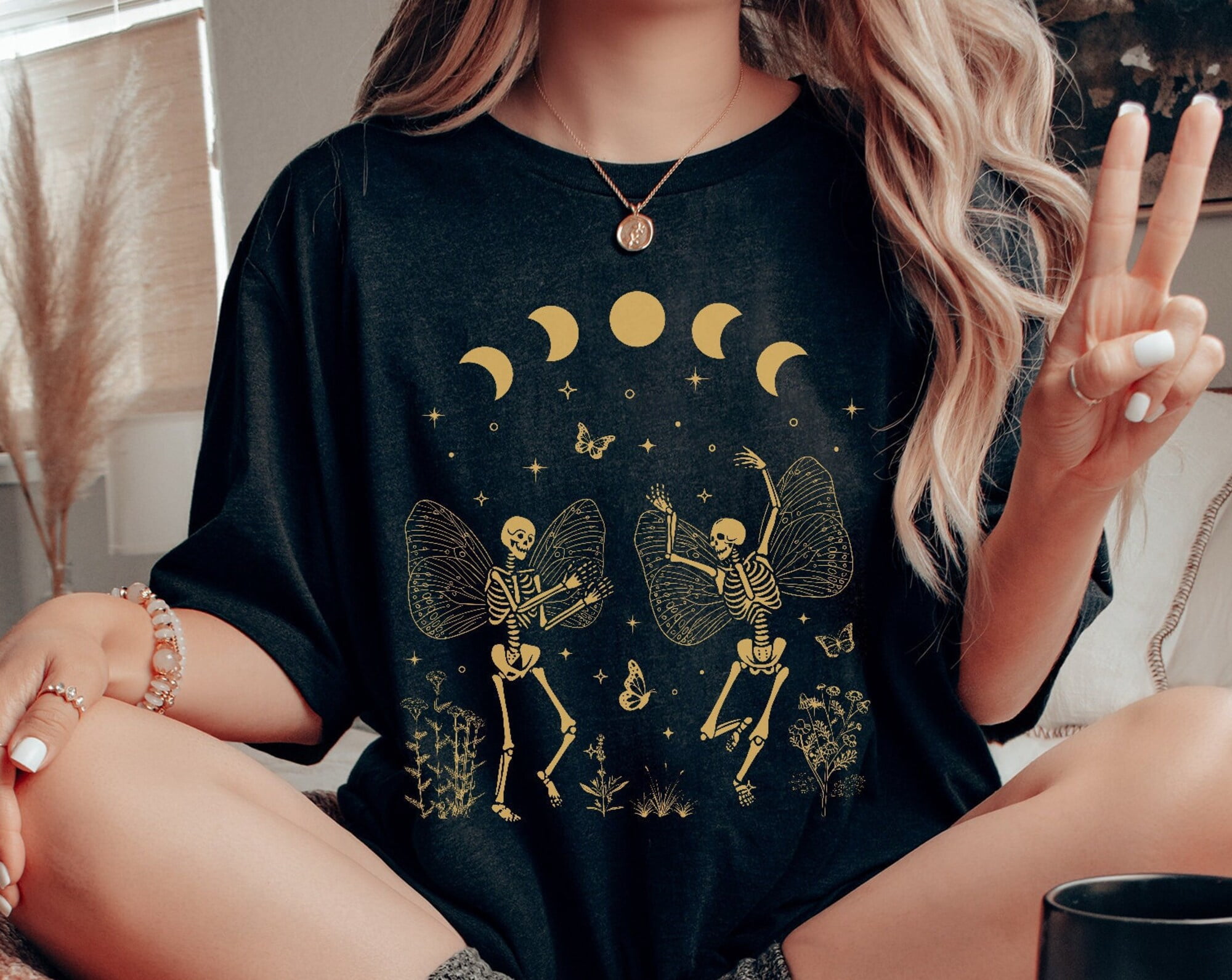 black tshirt with a graphic of two skeletons with wings dancing under a ...