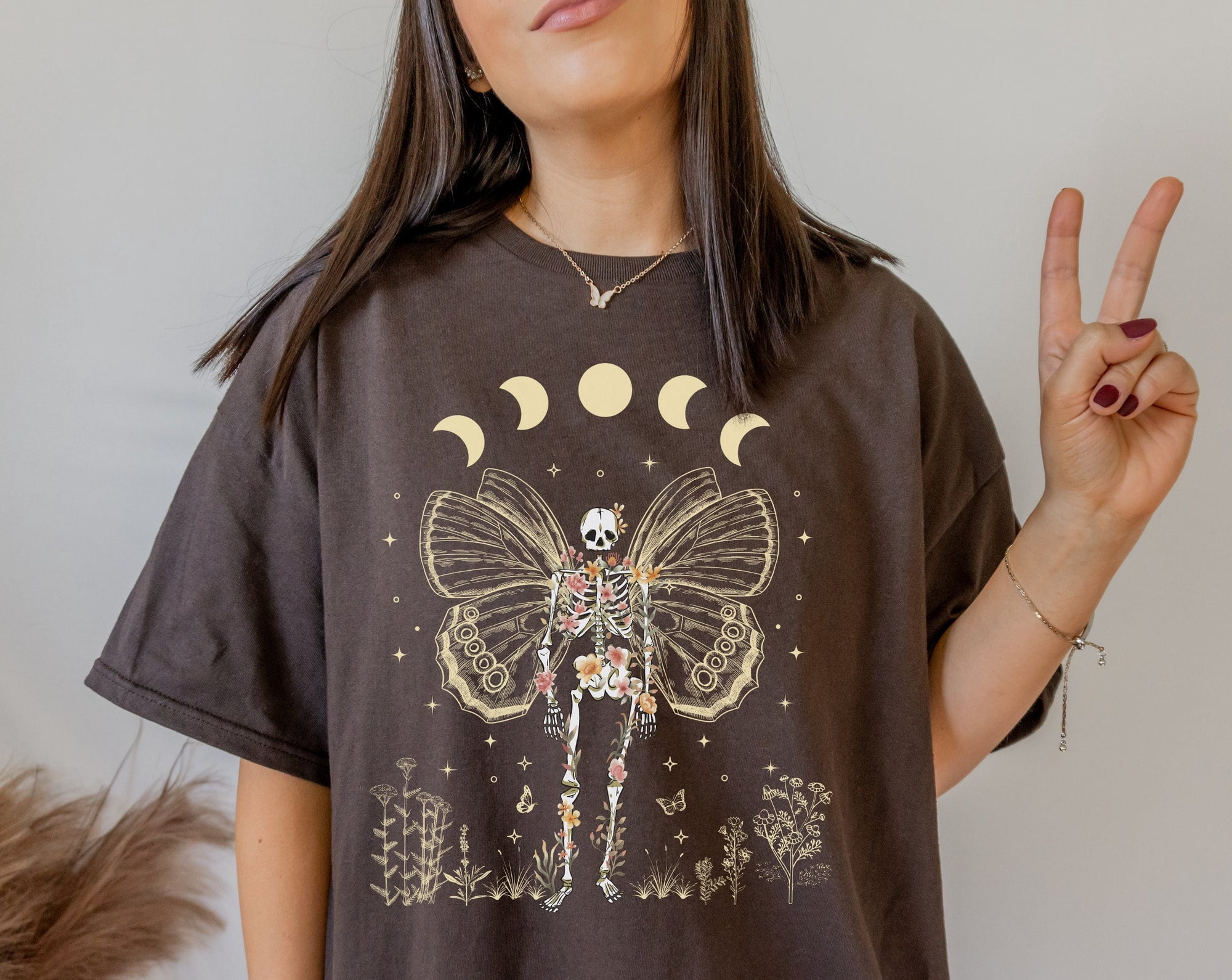 brown tshirt with a graphic of a skeleton wearing butterfly wings and ...