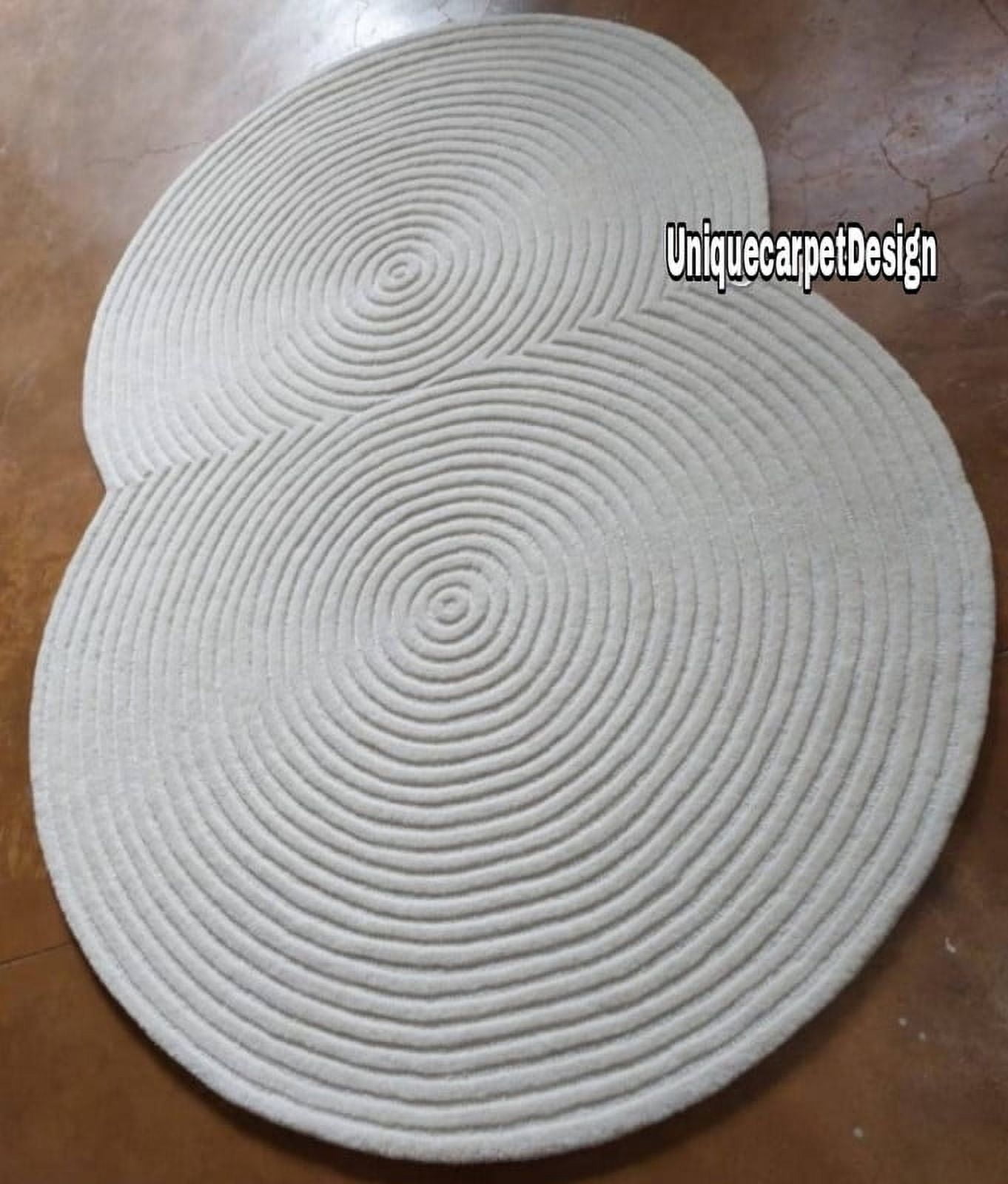 A handmade tufted woolen rug with a pile cut and loop design in white ...