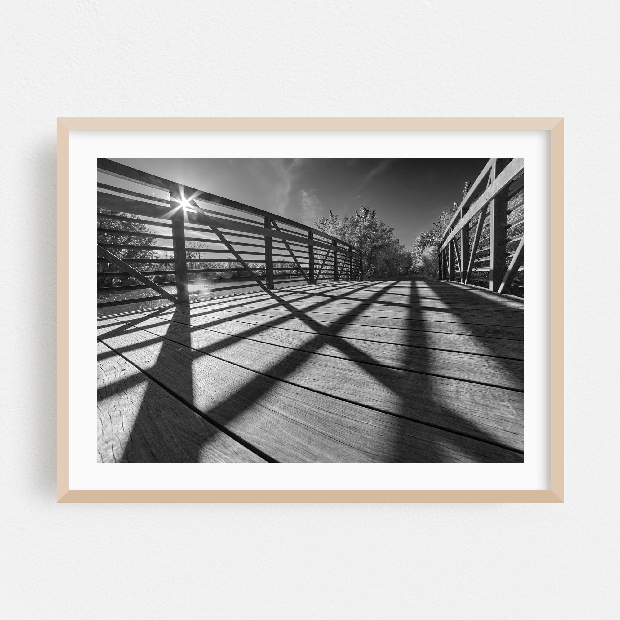The late day sun throws long shadows on this footbridge next to a small ...